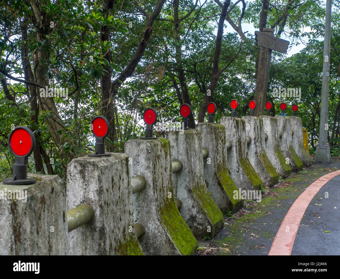 Concrete pillars / bumpers with red reflectors along asphalt road Stock ...