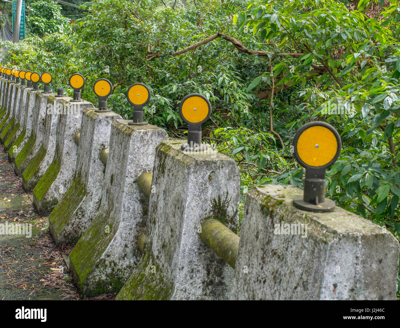 Concrete pillars / bumpers with yellow reflectors along asphalt road ...