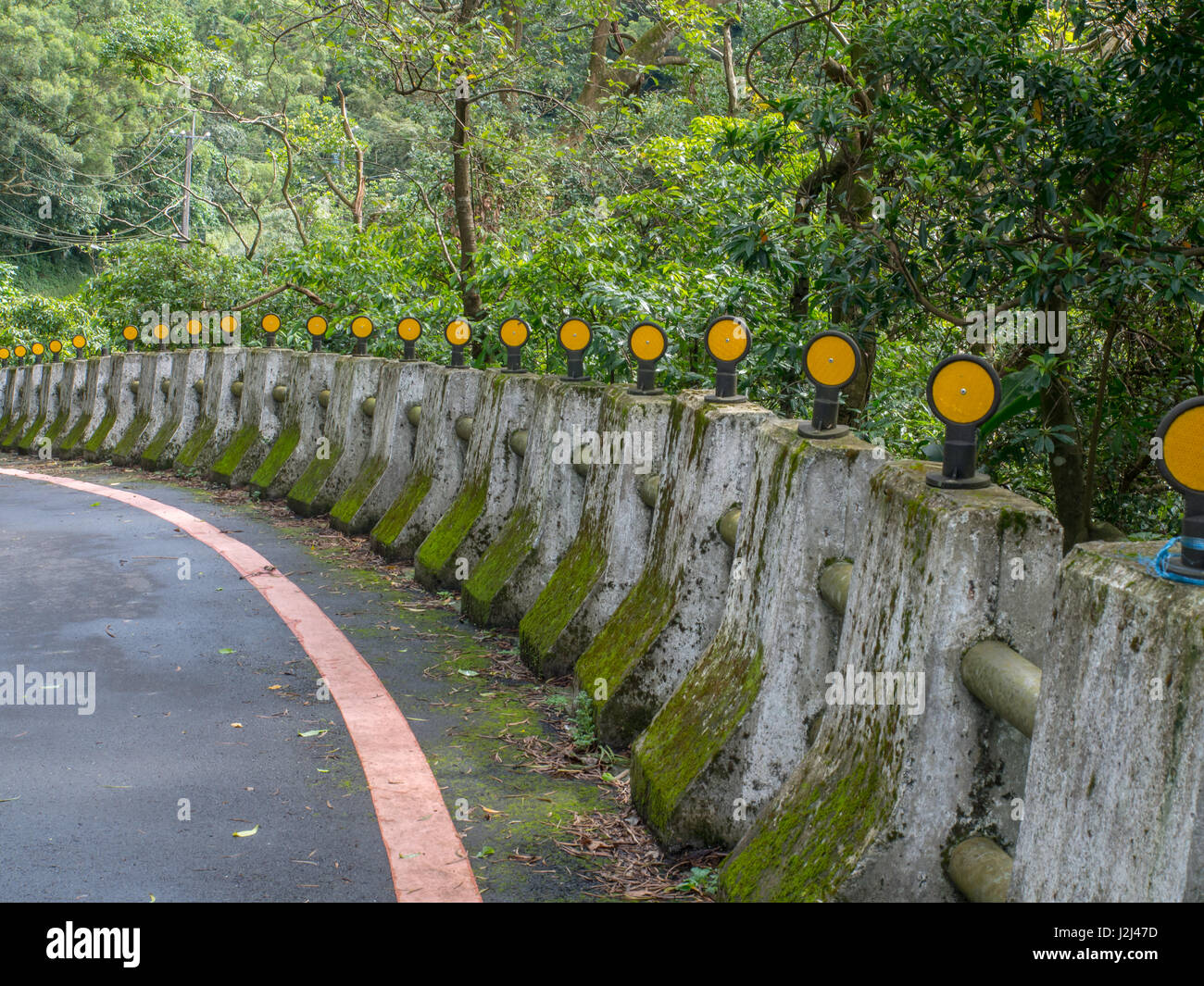 Concrete pillars / bumpers with yellow reflectors along asphalt road ...