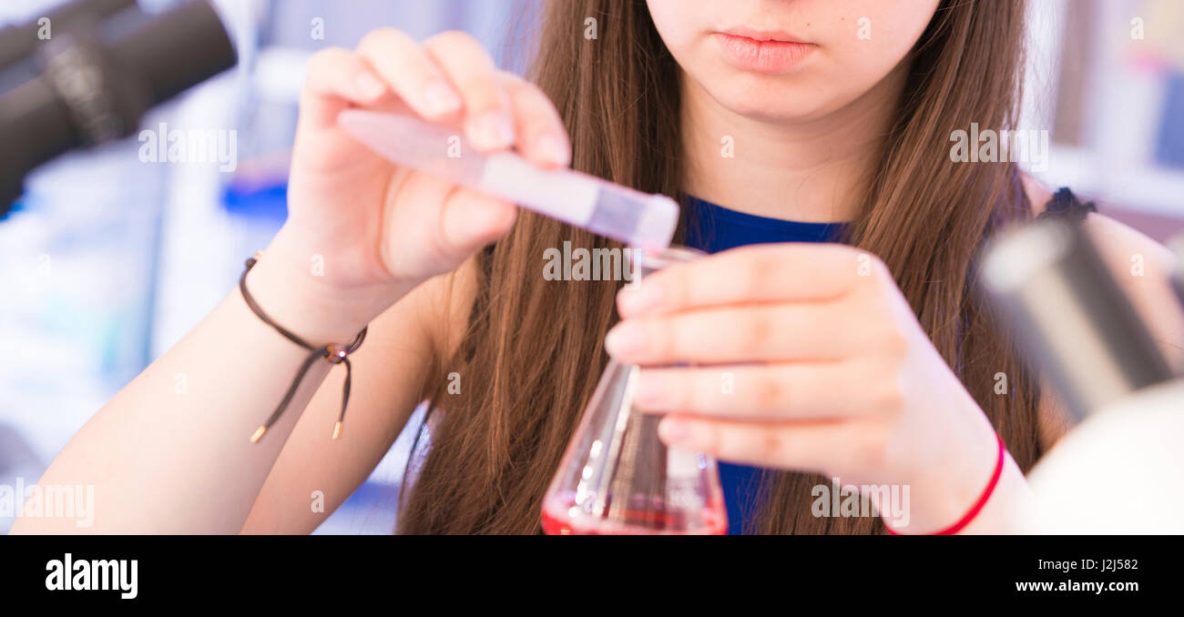 Chemistry student pouring liquid into beaker Stock Photo - Alamy