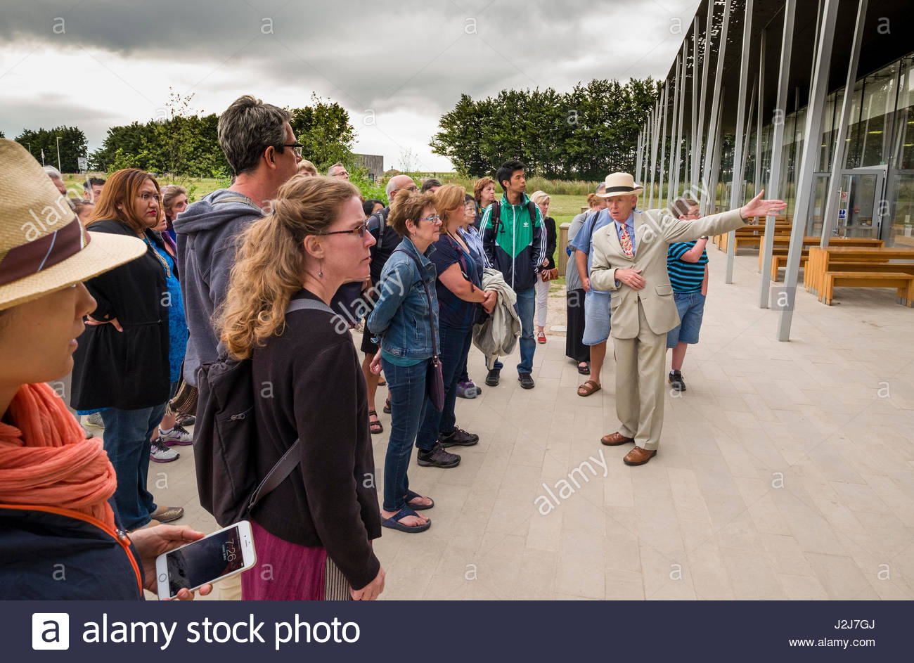 Male tour guide speaking to people in tour group about Stonehenge and ...