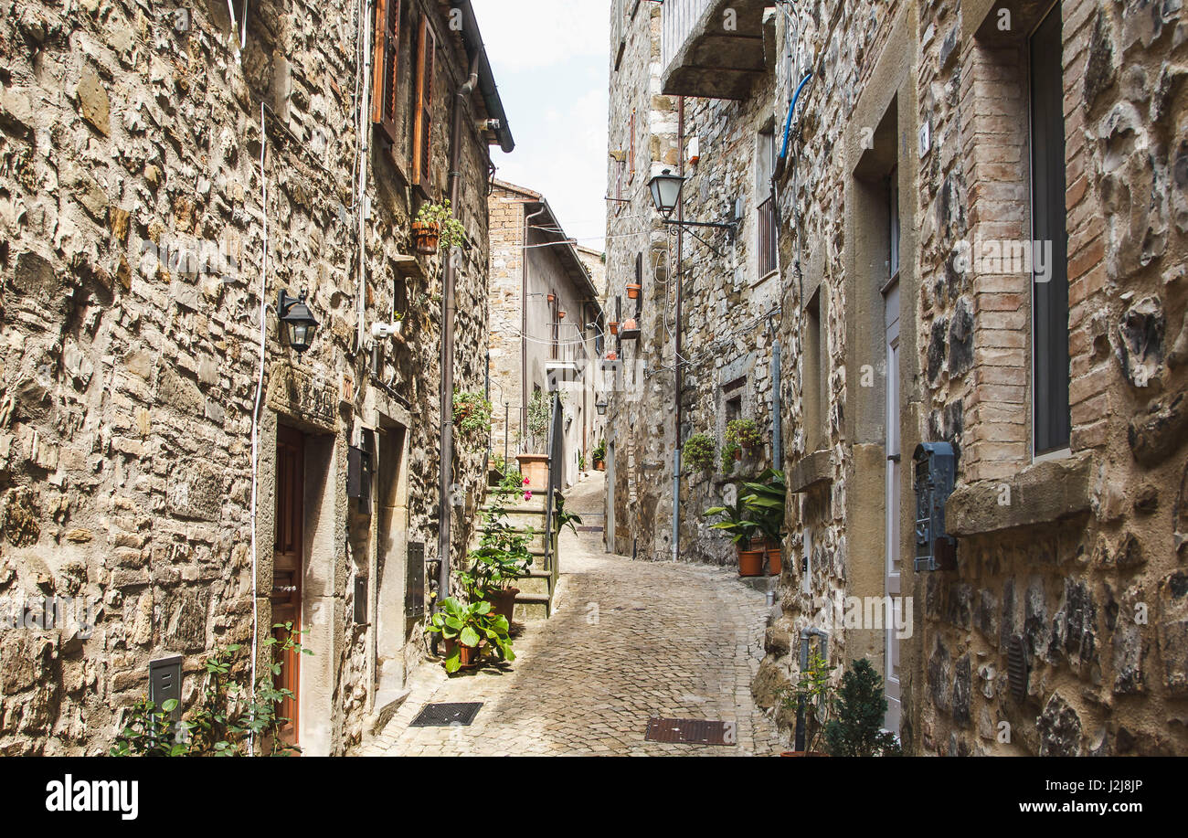A lane between two rows of houses with old masonry and stones. Italy ...