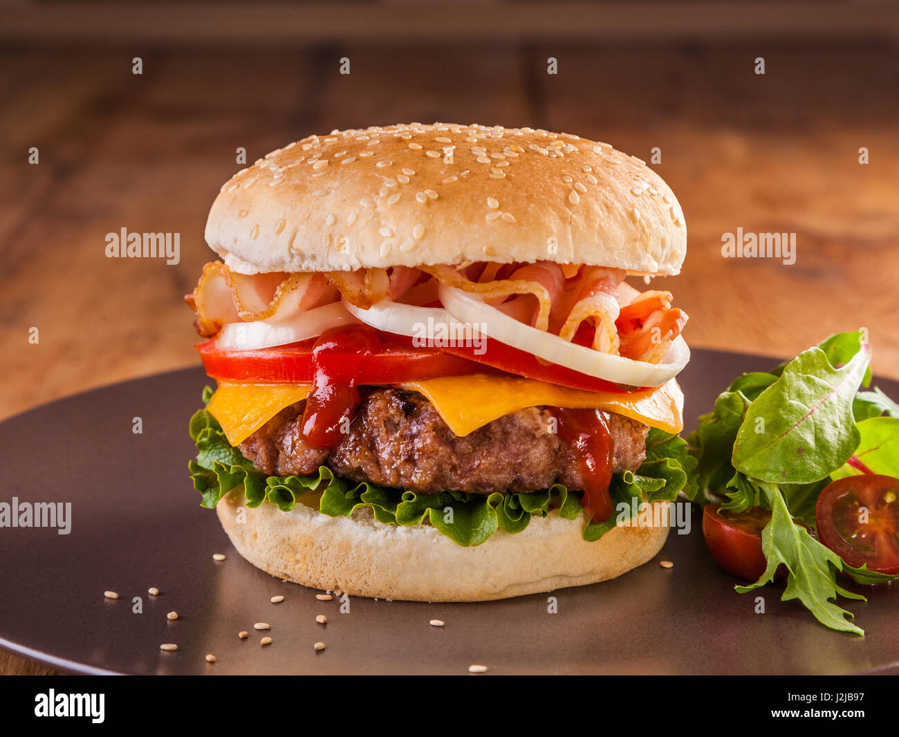 A juicy charcoal broiled hamburger with bacon, onion rings, tomato ...