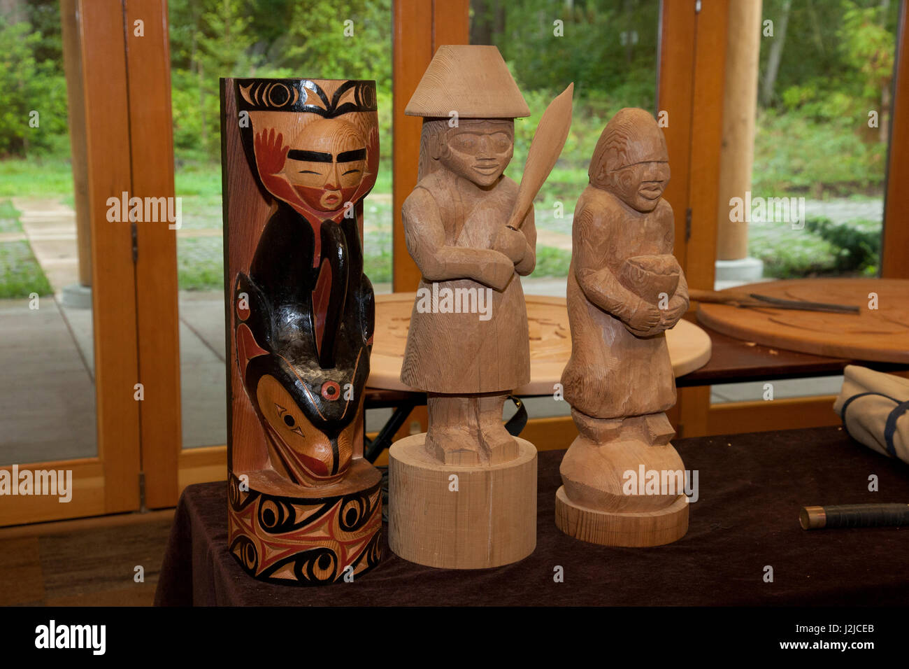 Miniature scale carved wooden totems are made before a larger totem ...