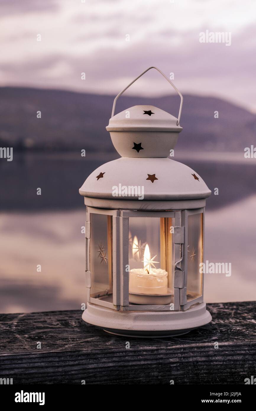 White lantern on wooden pier. Beautiful, calm lake in the background ...