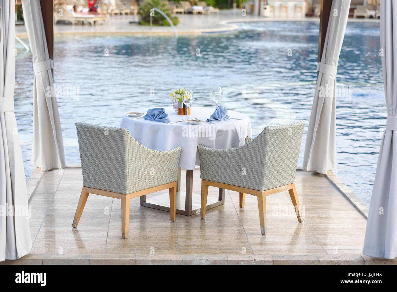 Dinner table for couple with white tablecloth and blue napkins by the ...