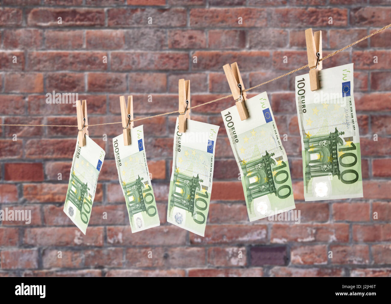 100 Euro banknotes hanging on clothesline on brick wall background ...