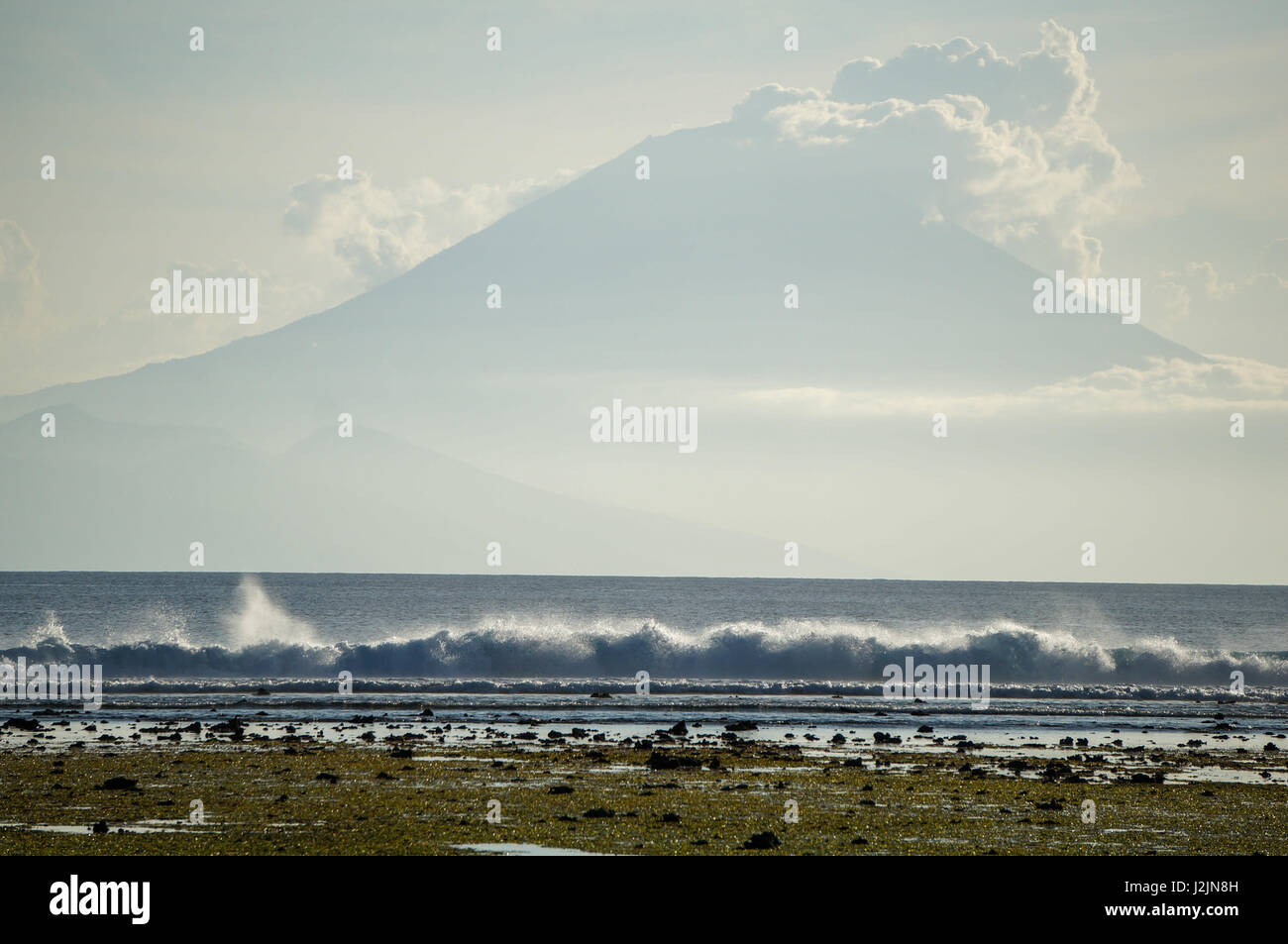 A view of a cloud-covered volcano in the distance Stock Photo - Alamy
