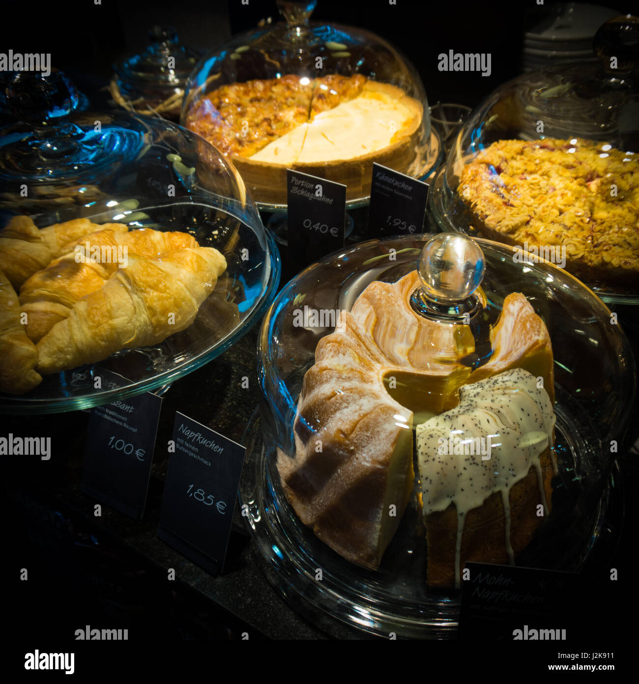 Cakes under bell-glass on display. bakery glass case full of different ...