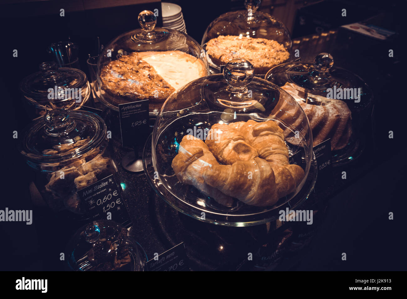 Cakes under bell-glass on display. bakery glass case full of different ...