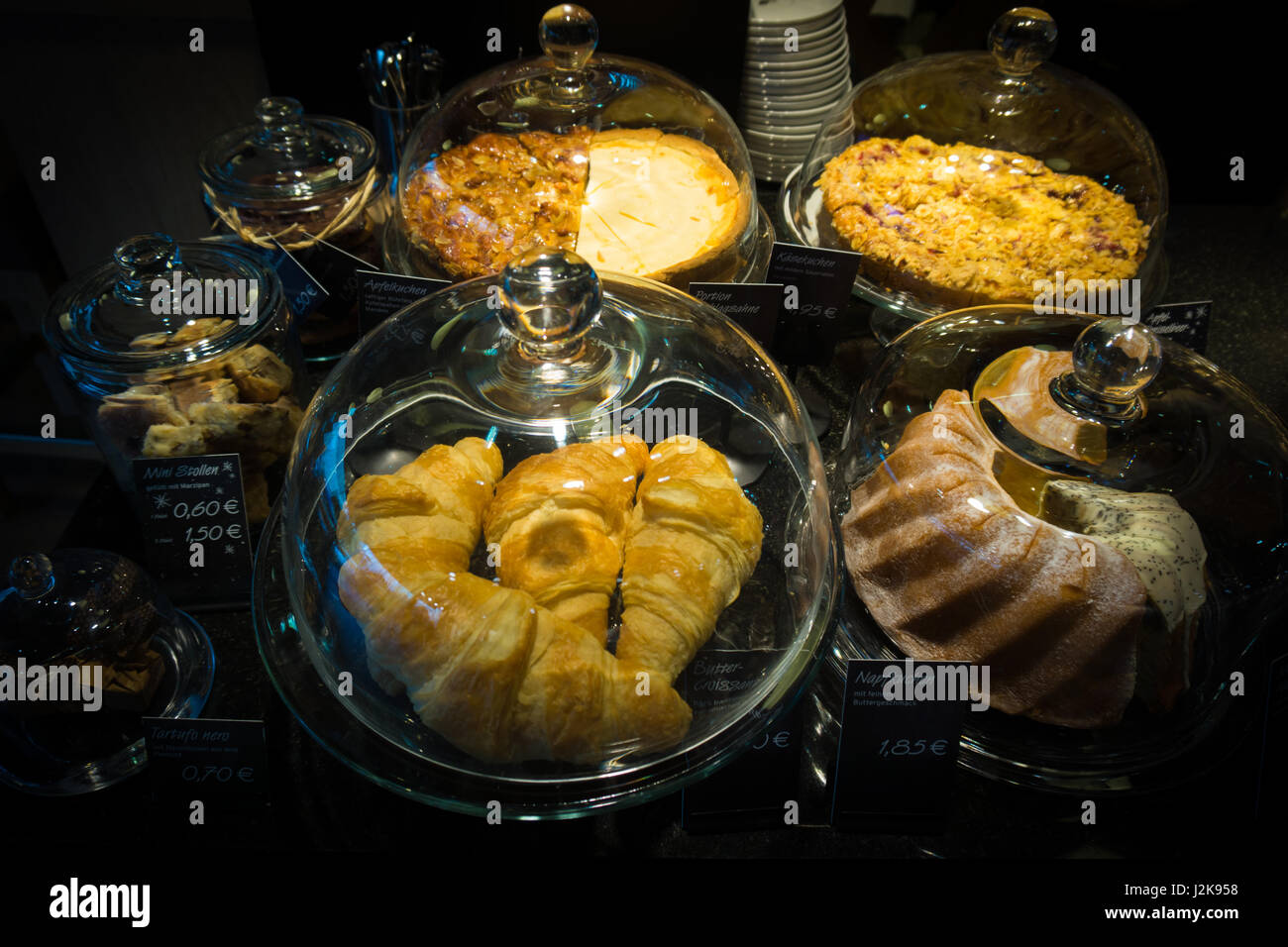 Cakes under bell-glass on display. bakery glass case full of different ...