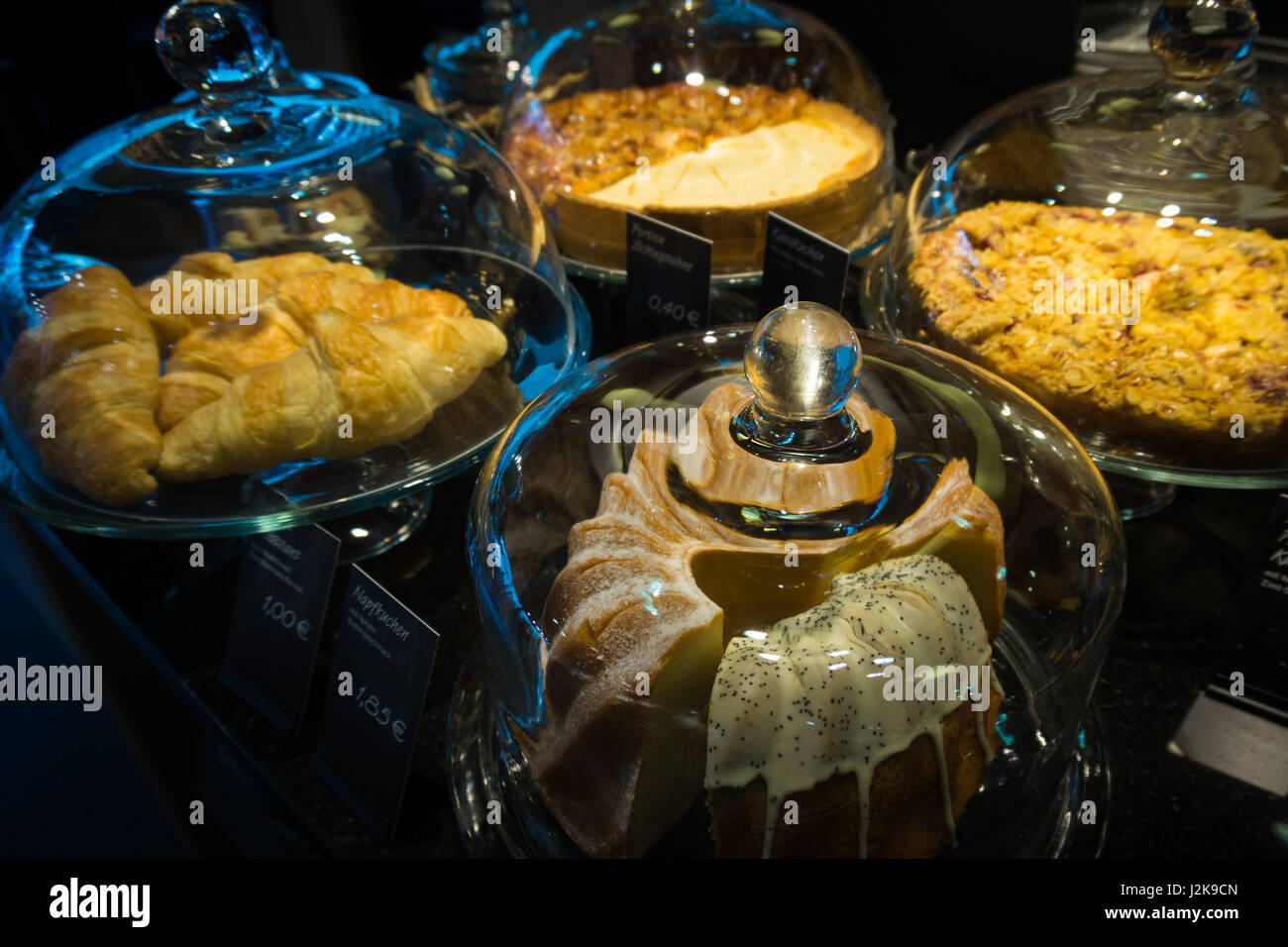 Cakes under bell-glass on display. bakery glass case full of different ...