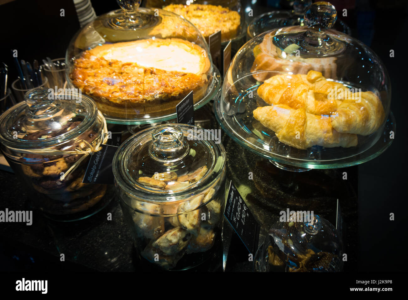 Cakes under bell-glass on display. bakery glass case full of different ...