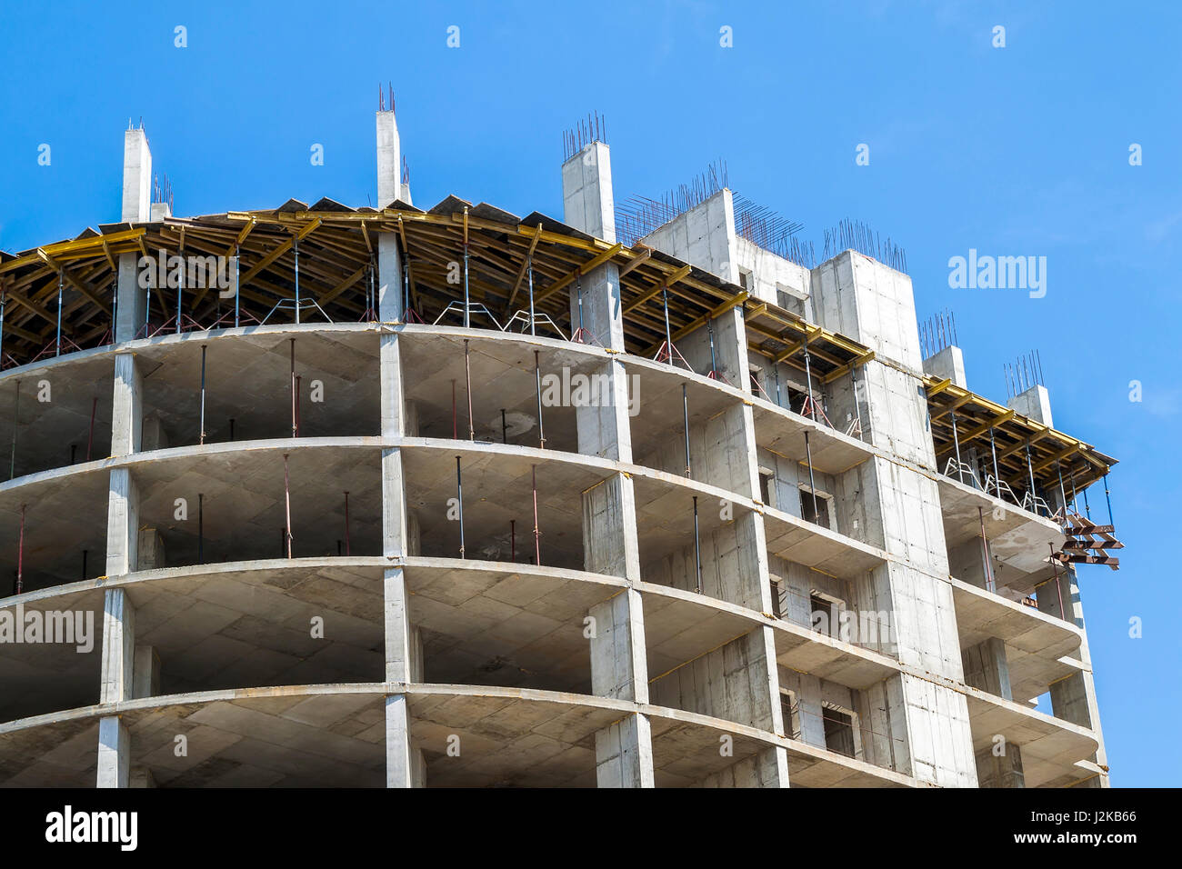 Modern building under construction against blue sky. Construction work ...