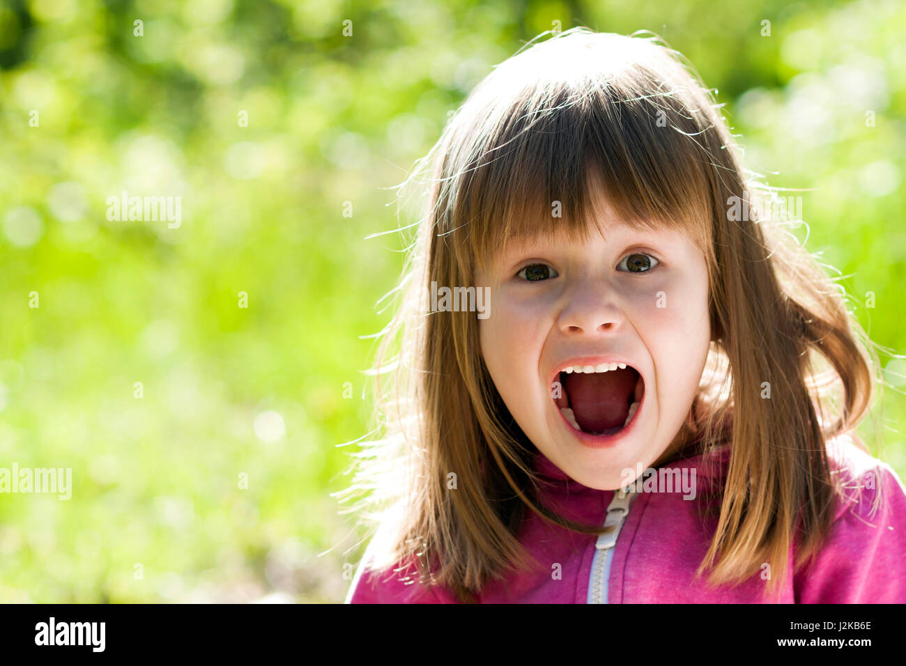 Close-up portrait of a little pretty girl with shouting face expression ...