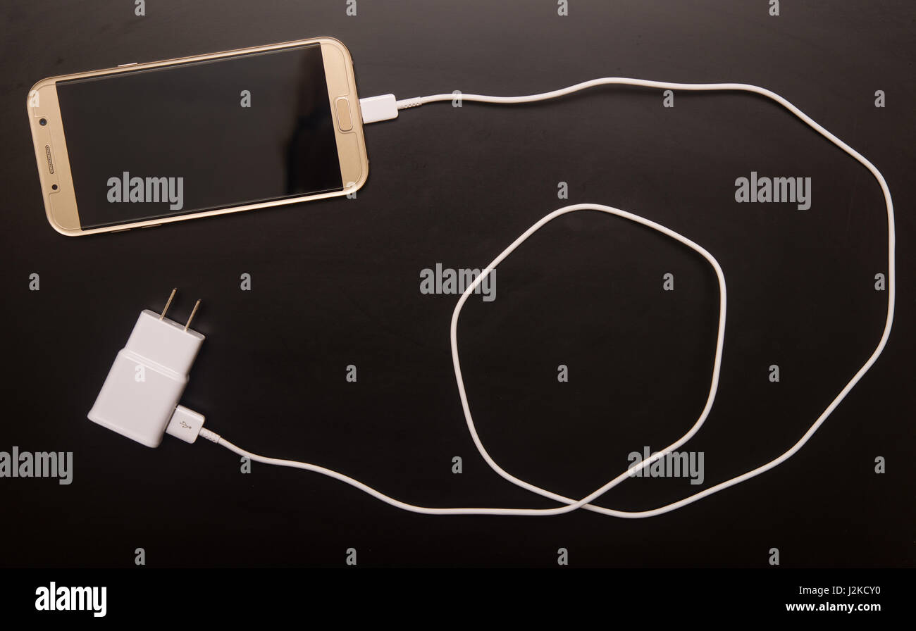 Phone with charger on black background Stock Photo - Alamy