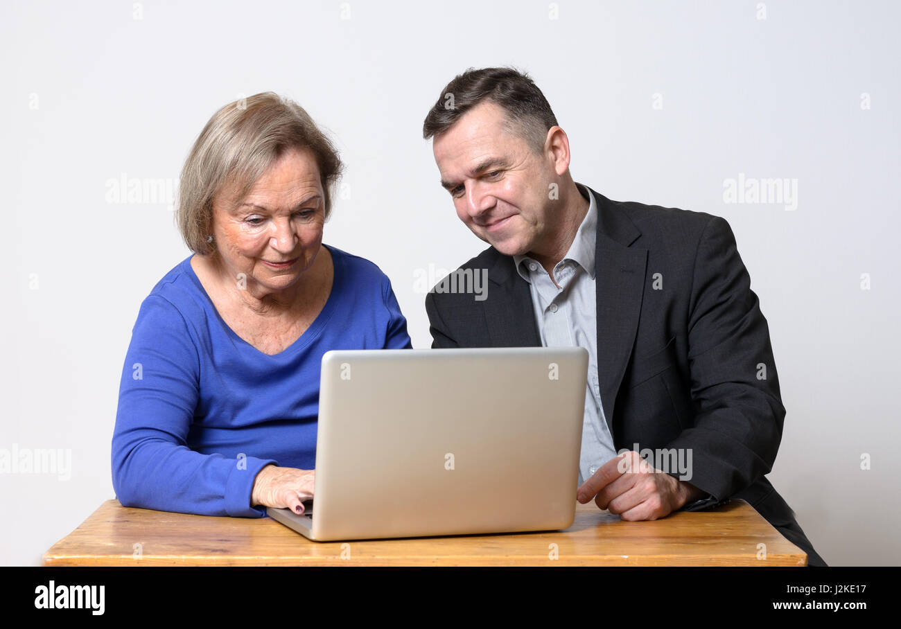 Cheerful cute senior woman in blue shirt using computer beside smiling ...
