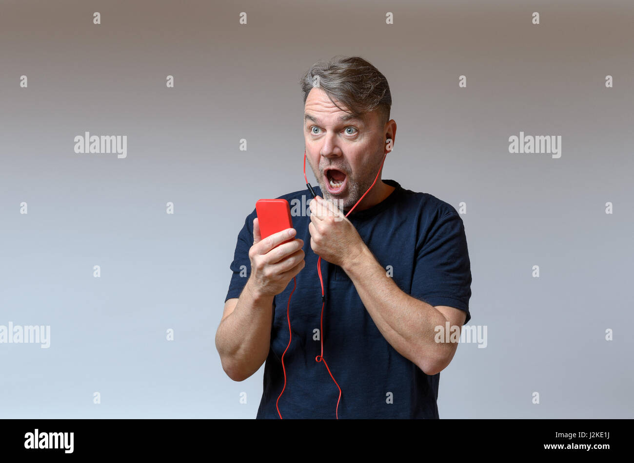 Middle-aged man standing looking up in shock and horror with wide eyes ...