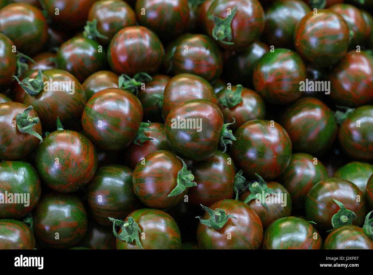 Green and red Kumato fresh small cherry tomatoes background, close up ...