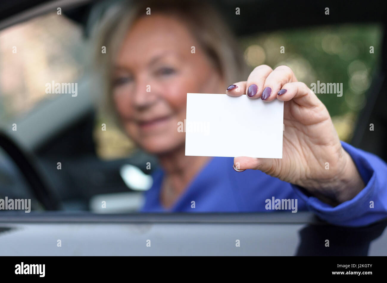 Elderly woman leaning through the open window from the drivers seat of ...