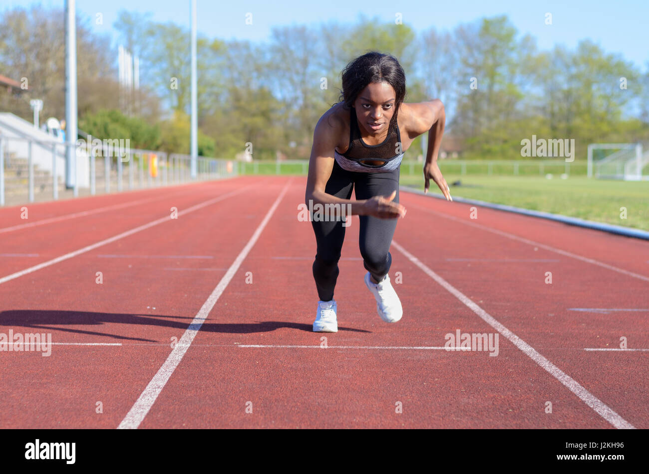 Young African woman doing sprint training on a sports track launching ...