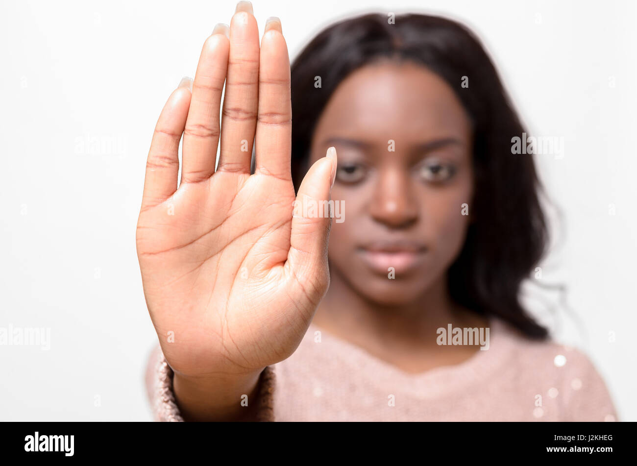 Stern young African woman making a halt or stop gesture raising the ...