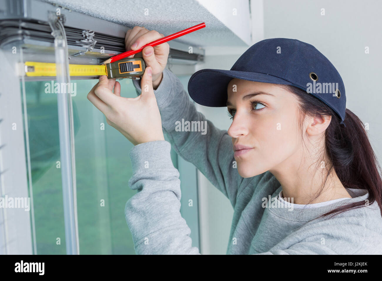 Woman using tape measure and marking position Stock Photo - Alamy
