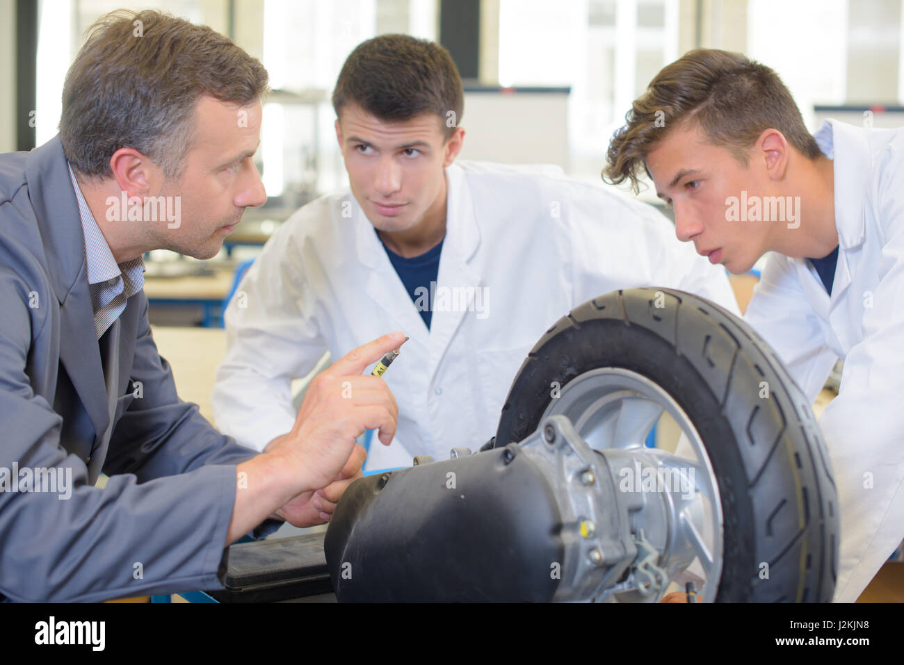 Mechanic with wheel teaching apprentices Stock Photo - Alamy