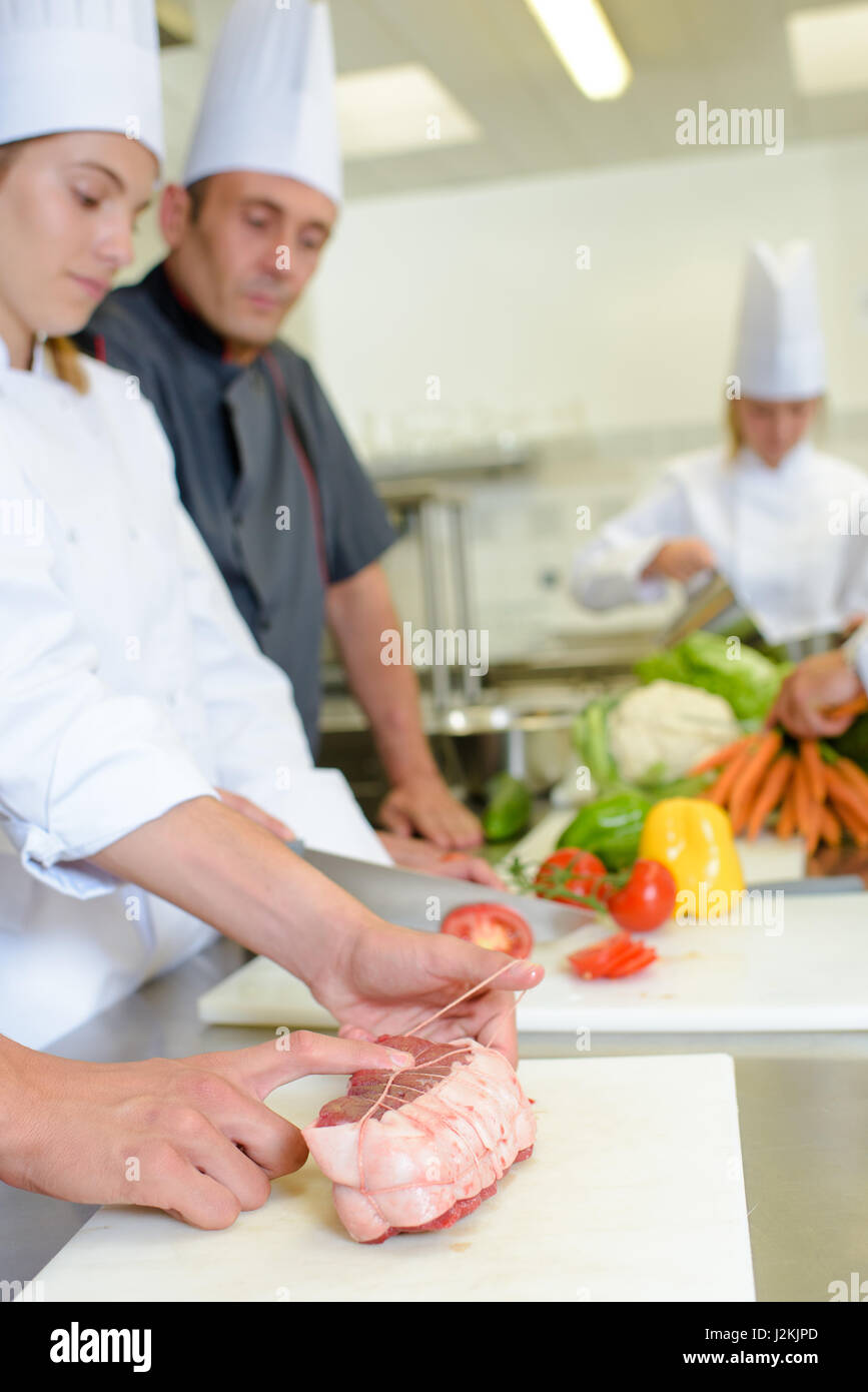 Trainee chef learning to tie a joint of meat Stock Photo - Alamy