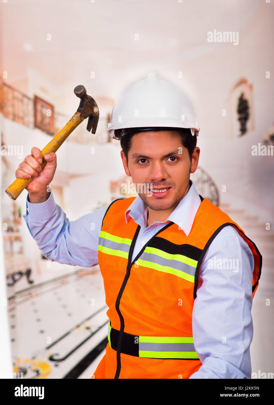 Handsome young engineer holding a hammer in his hand at construction ...