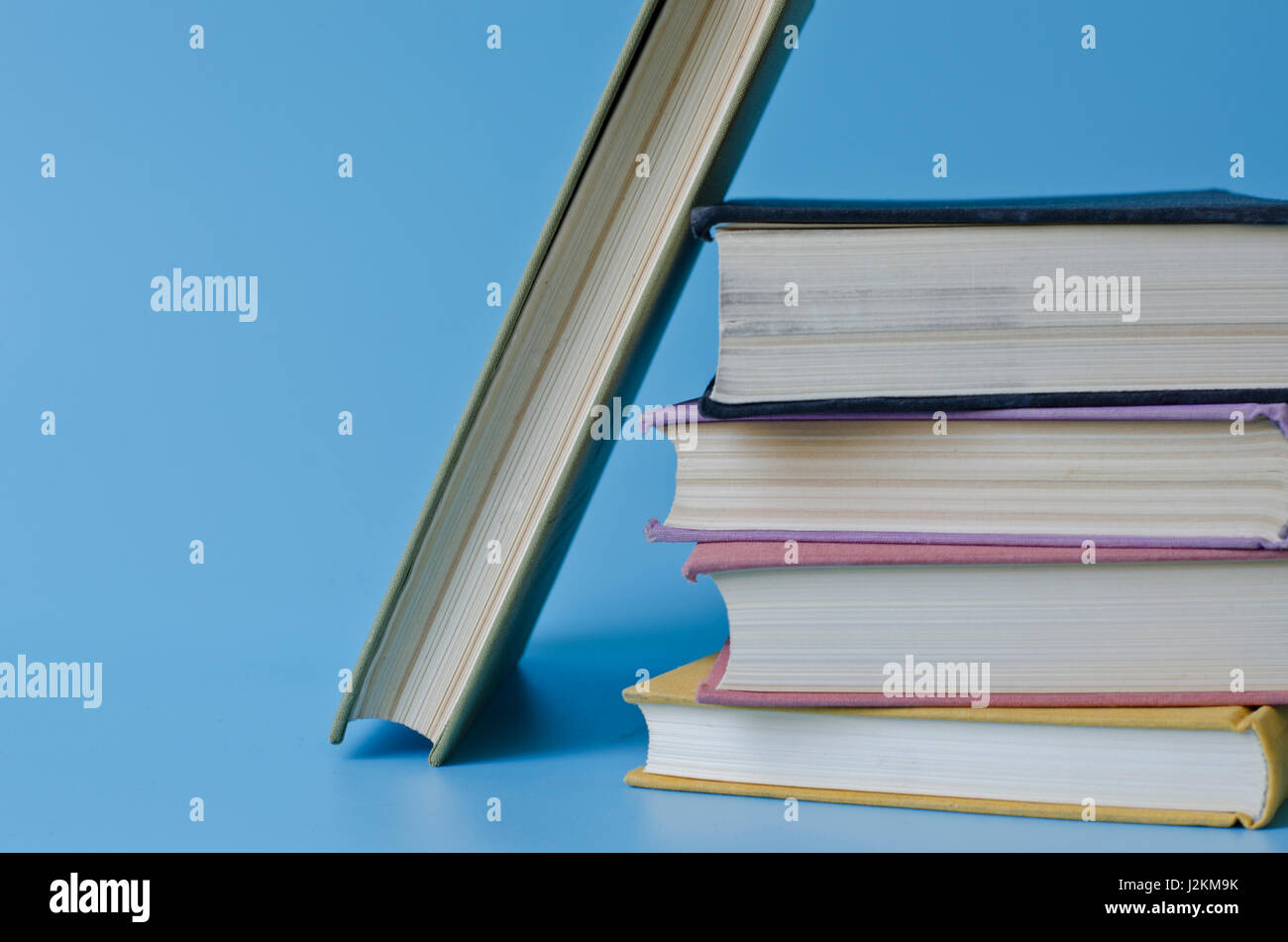 a stack of colorful books on a blue background in library Stock Photo ...