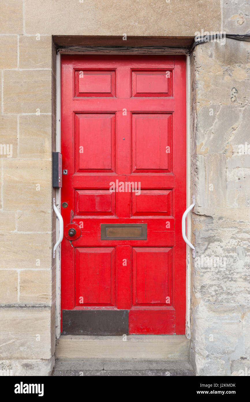 old, rustic, and weathered red European door on thick stone residential ...