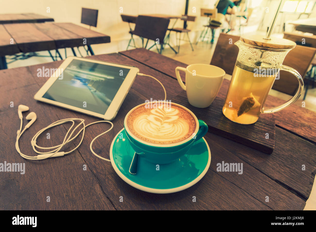 hot coffee and a pot of tea on wooden table with computer tablet and ...