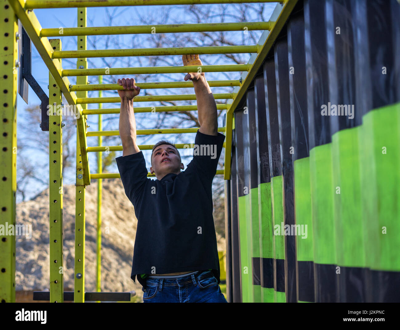 Male athlete swinging on monkey bars Stock Photo - Alamy