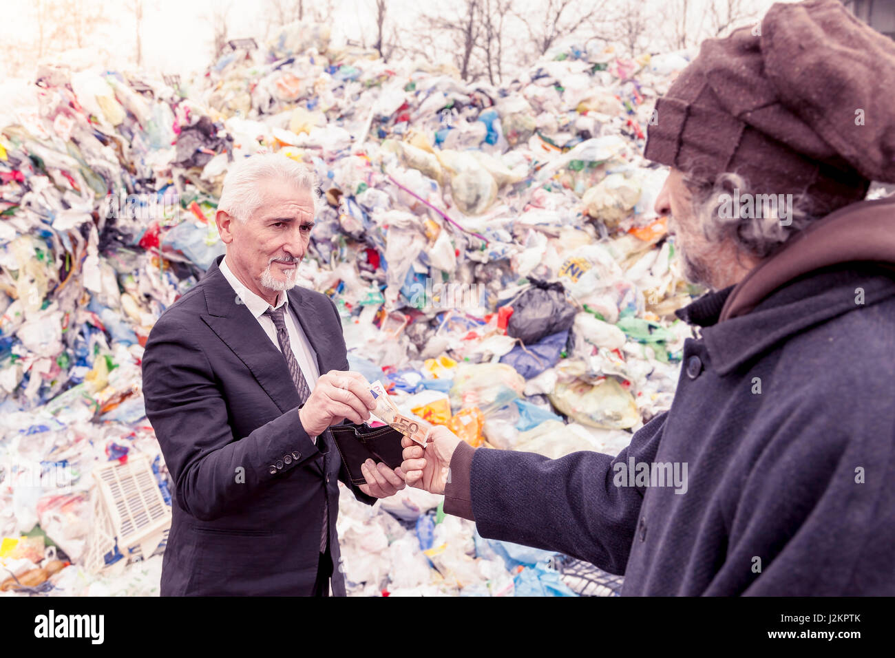 businessman gives money to a homeless man in a dump Stock Photo - Alamy