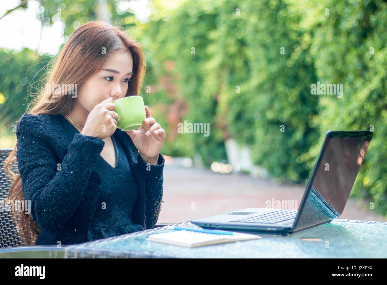 Young woman sips coffee and is sitting with her laptop in the morning ...