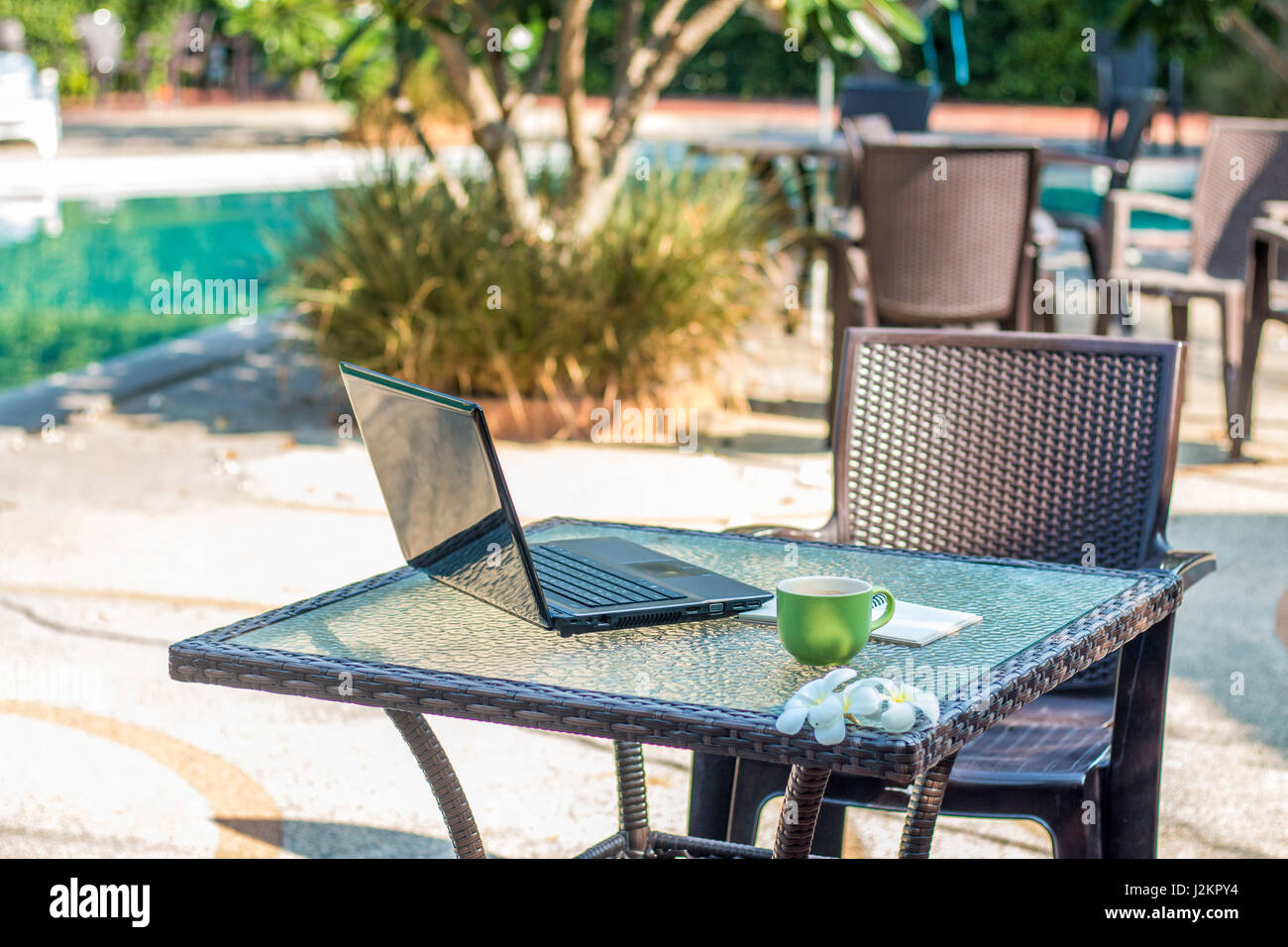 A poolside work desk with a table top, coffee mug and notebook is ...