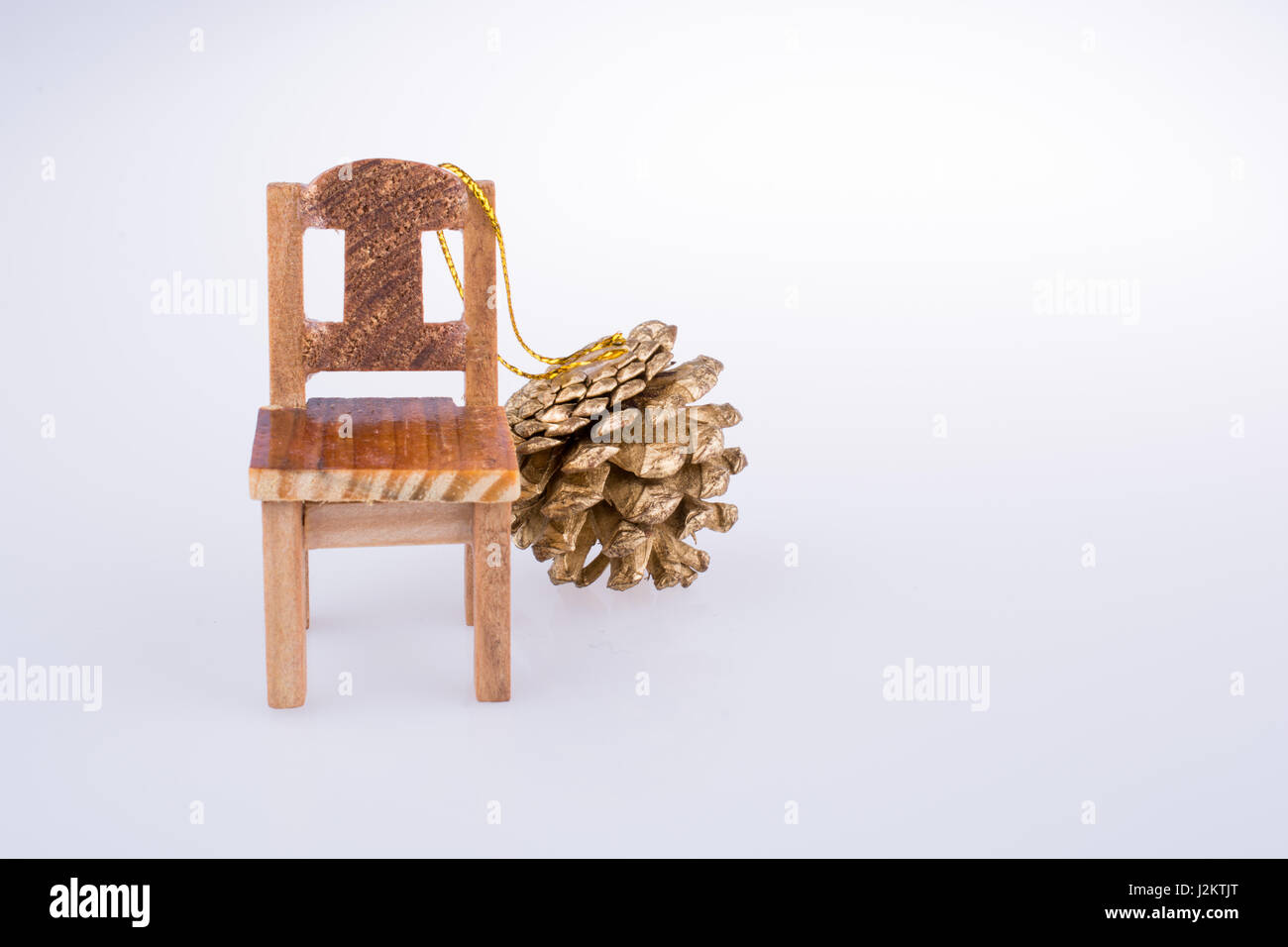 Pine cone bye the side of a model chair on a white background Stock ...