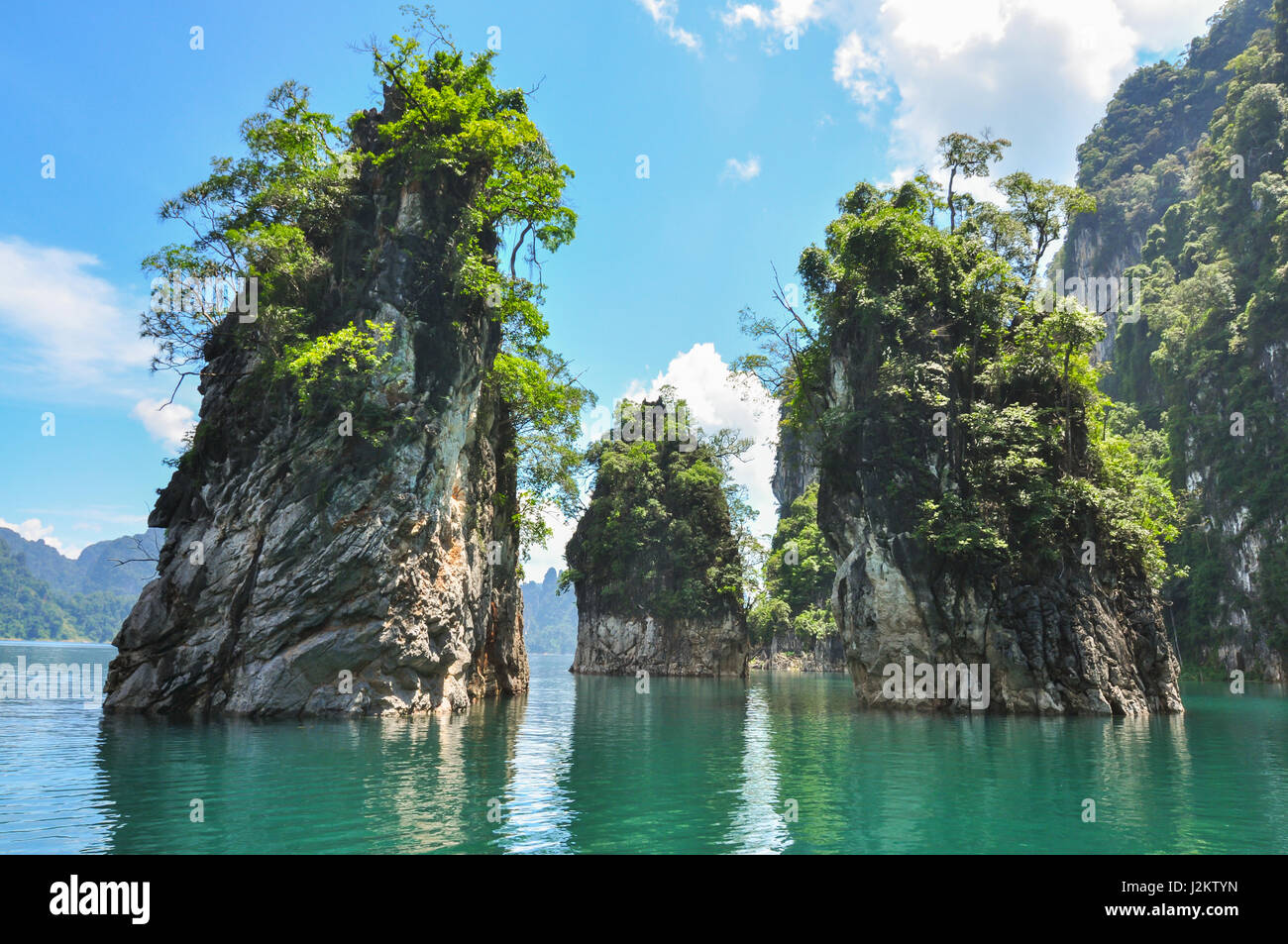 Huge limestone cliffs rising out of open lake at Khao Sok National Park ...