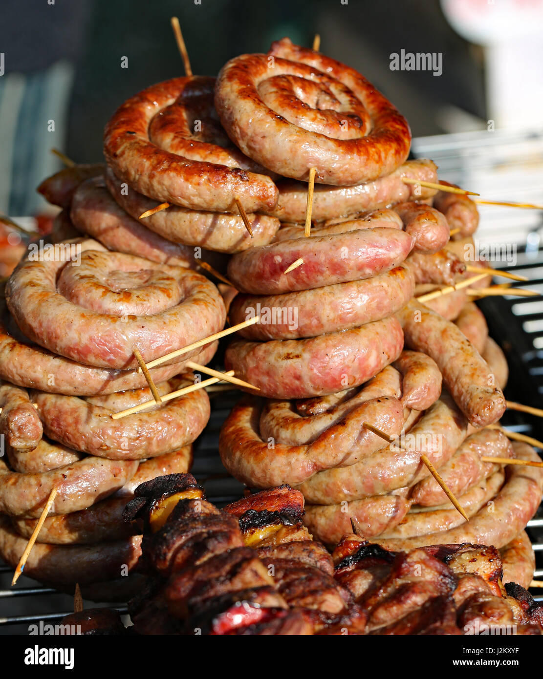 pile of cooked meat with rolled sausage and pork skewers on the grill ...