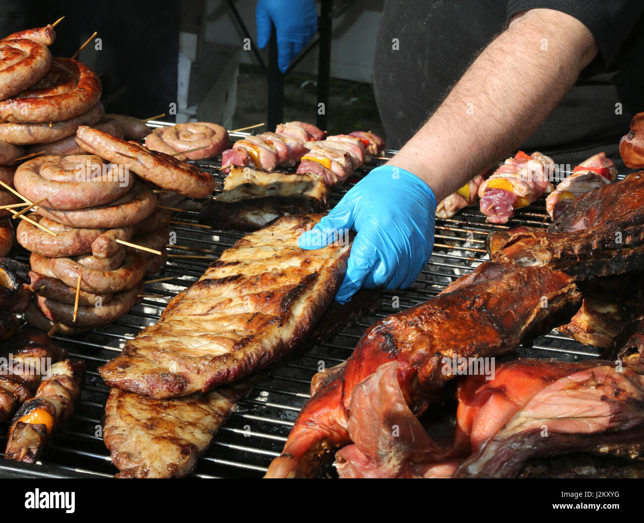 cook with blue gloves verifies the perfect cooking of pork ribs on the ...