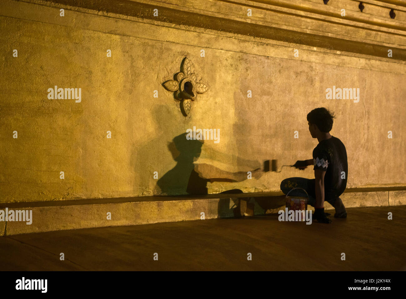 a painter is painting the Stupa with golden colours at the Pha That ...