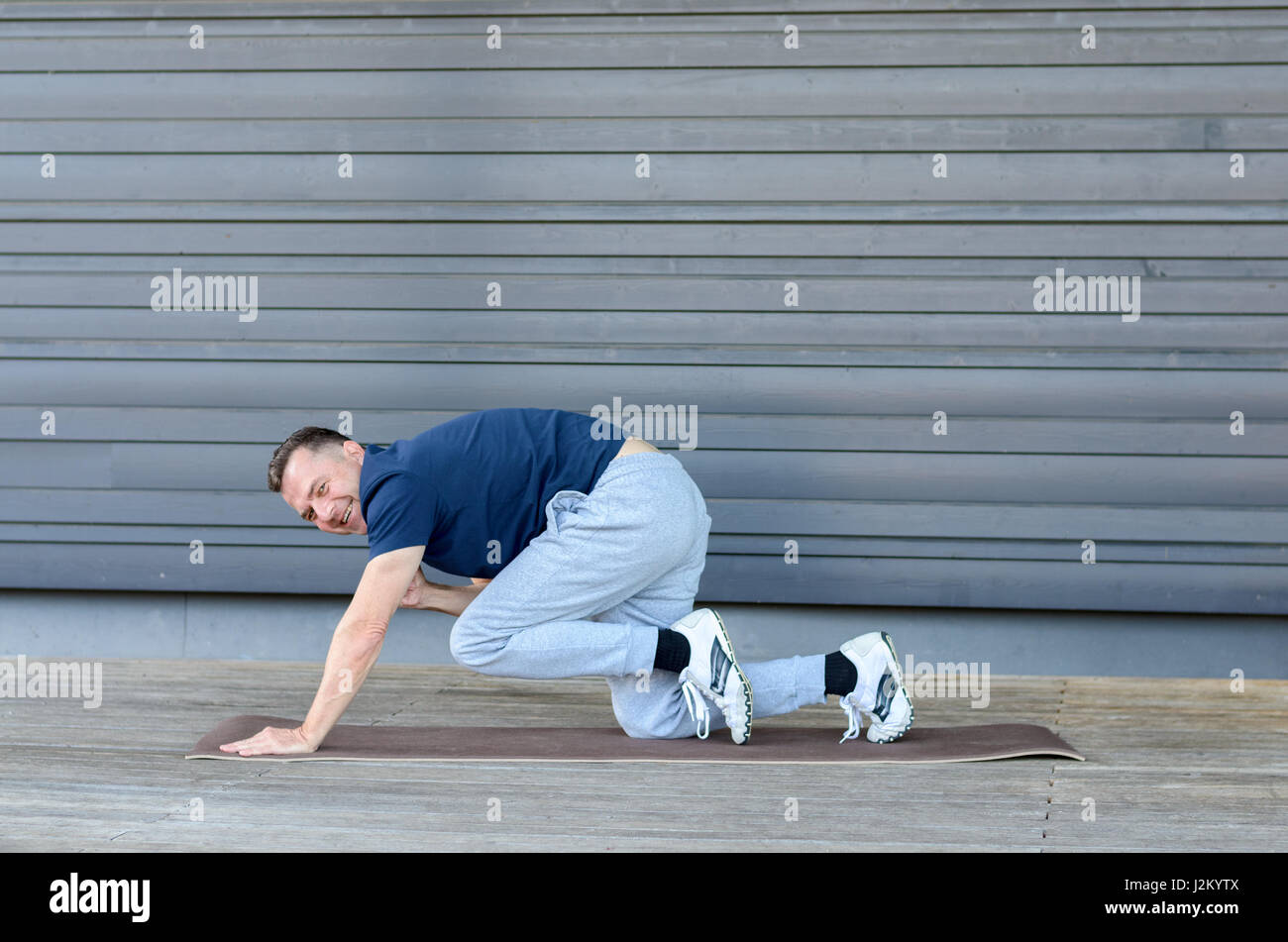 Adult man stretching in plank with one leg and one hand raised and ...
