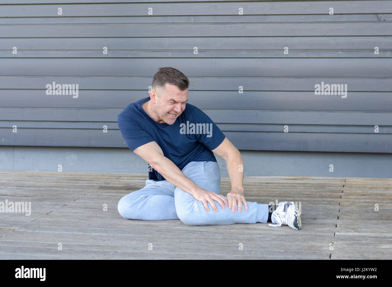 Sporty middle-aged man with muscle cramps in his calf lying on the ...