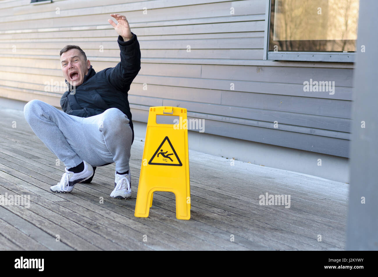 Middle-aged man yelling out in pain after falling on a slippery wooden ...