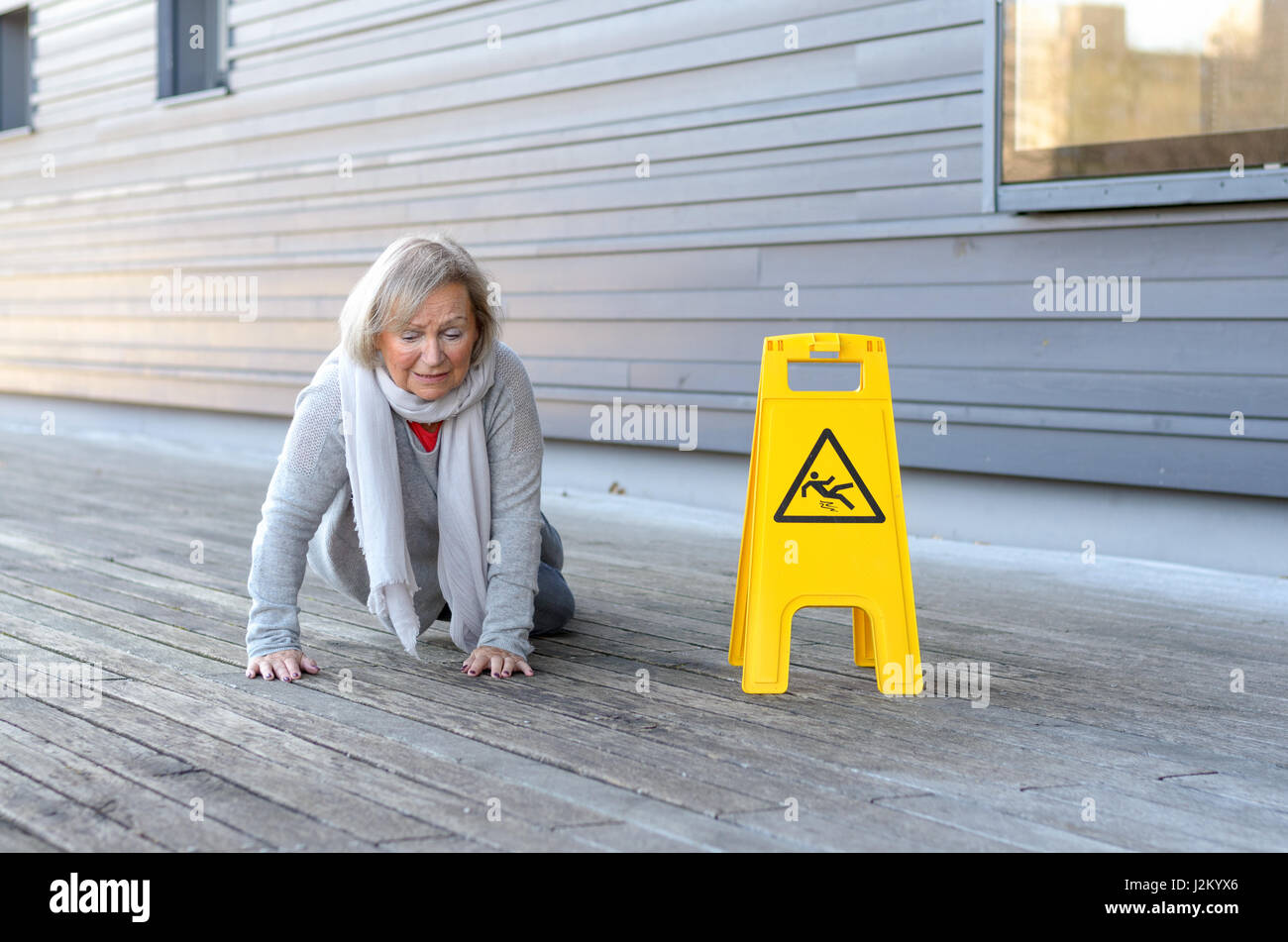 Senior lady slipping and falling on a wet surface with a grimace of ...
