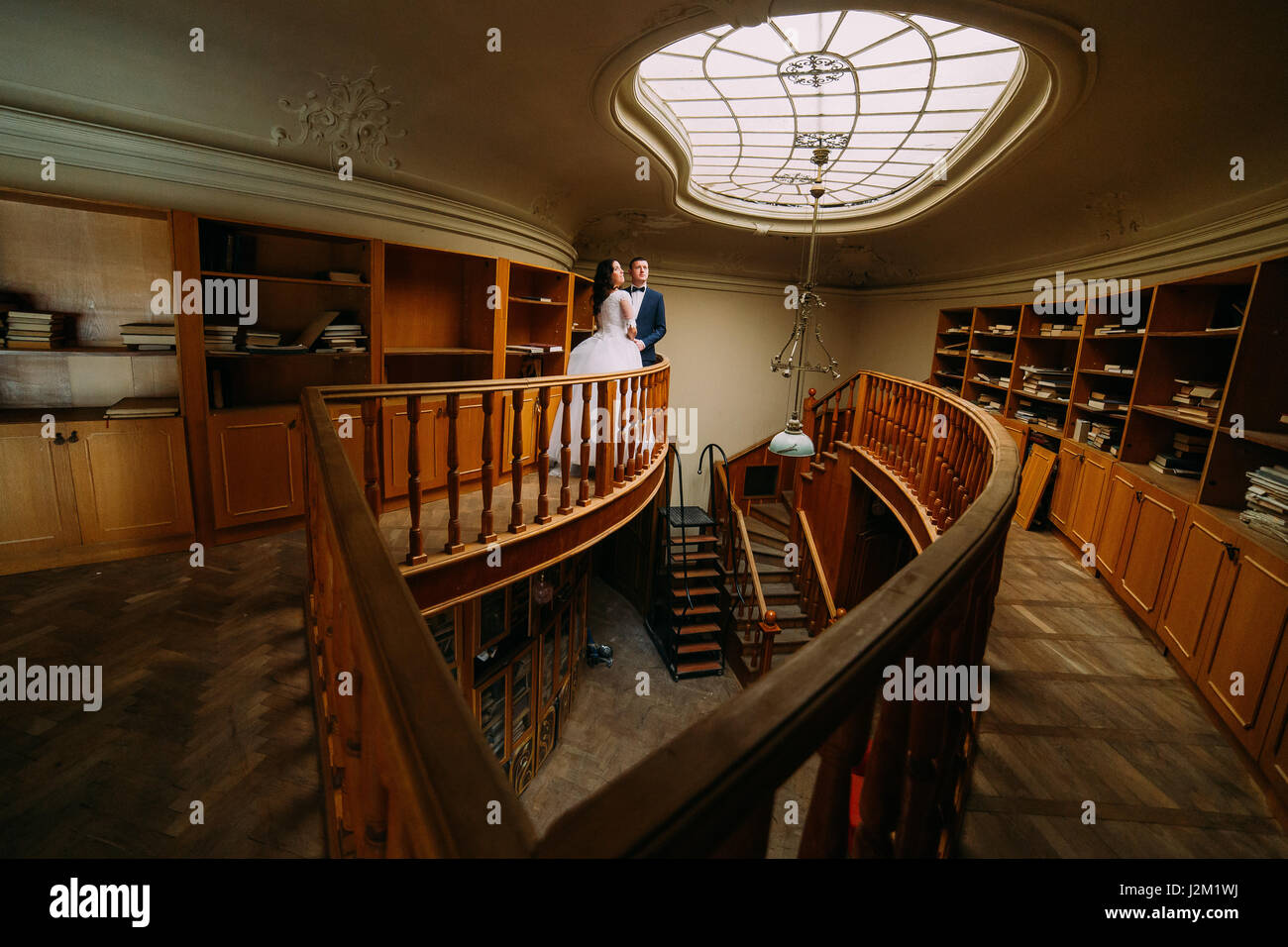 Elegant newlywed couple posing at old library with fancy vintage ...