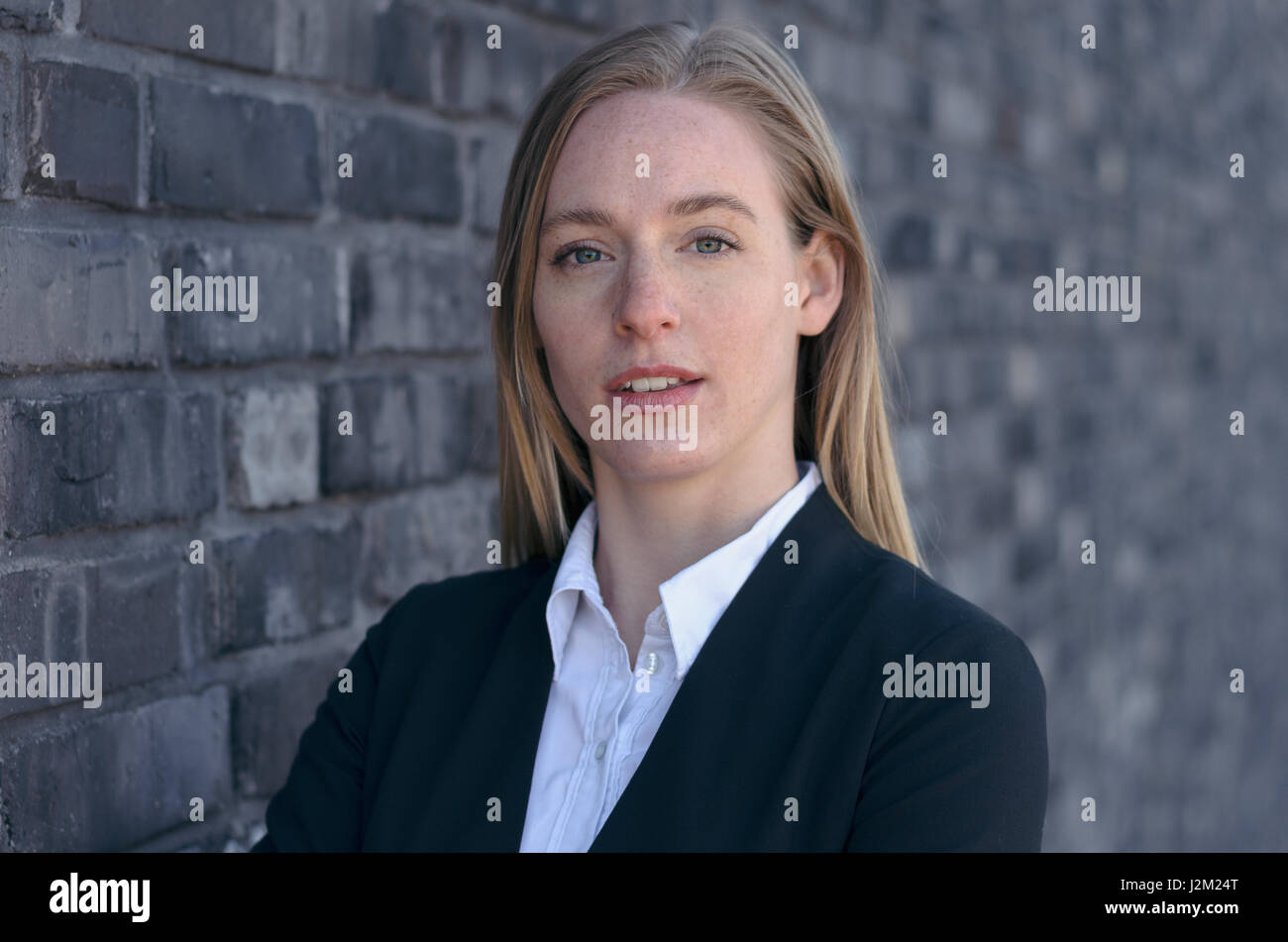 Single pretty young adult blond woman with long hair smiling near gray ...