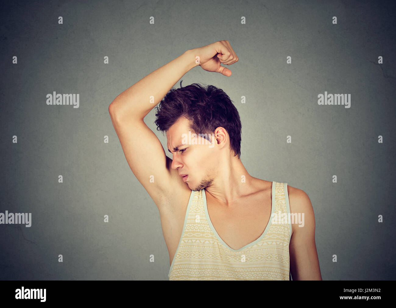 Closeup portrait of young man, smelling, sniffing his armpit, something ...