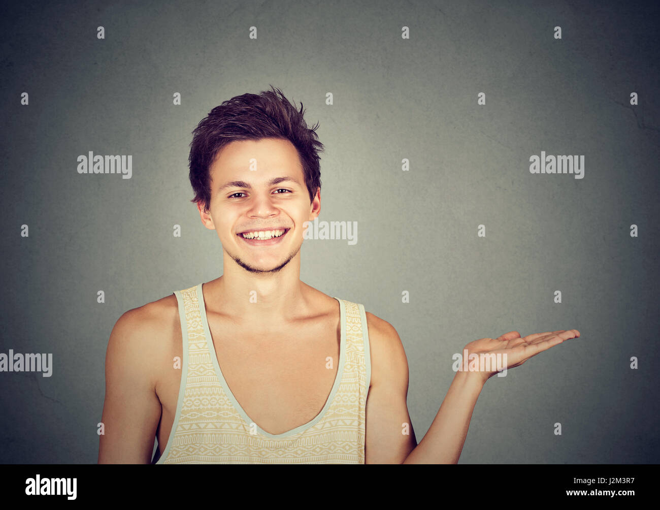 Happy young smiling man pointing to blank space isolated on gray ...
